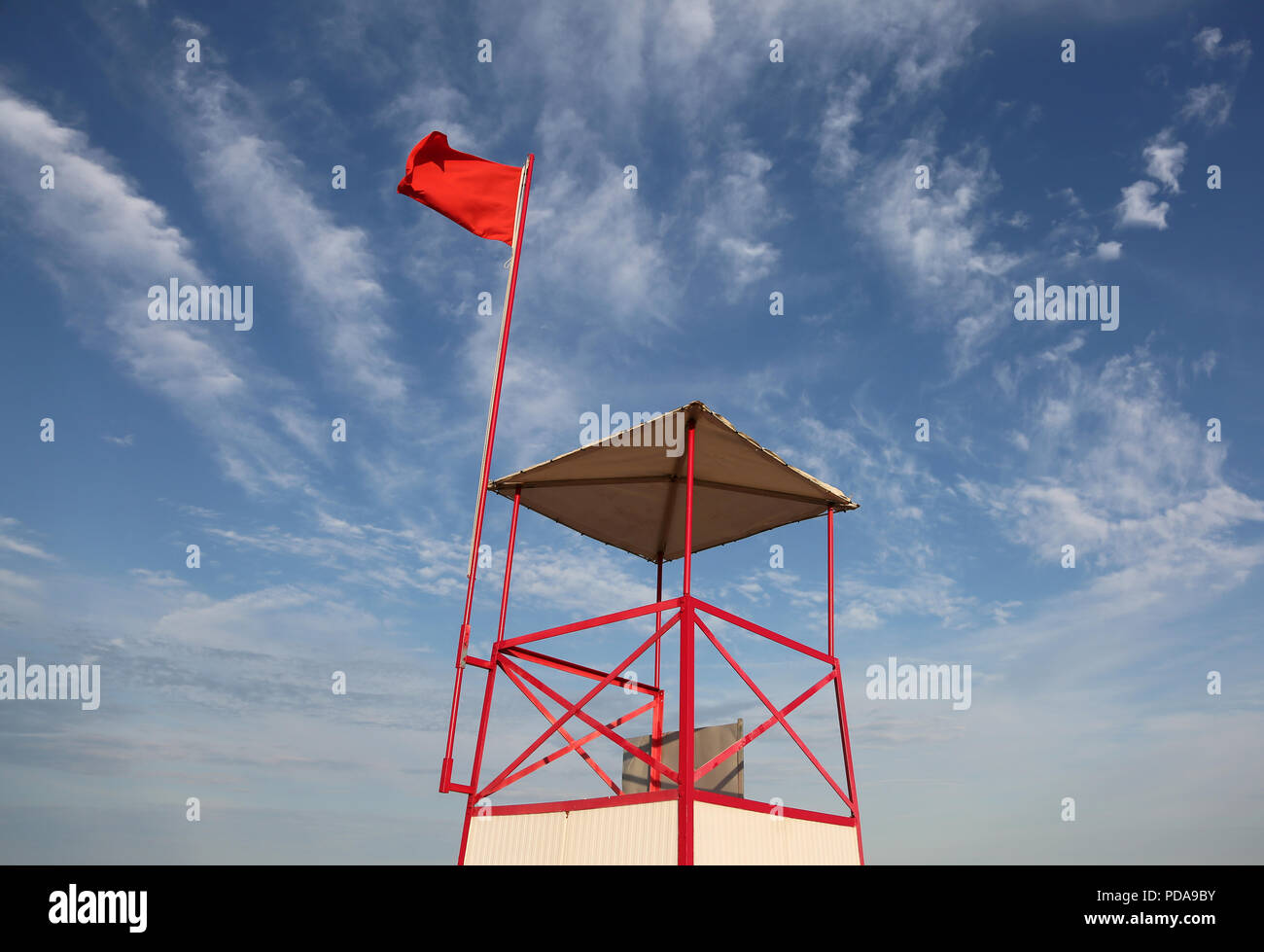 Lifeguard watchtower on the beach with the big red flag waving in the ...