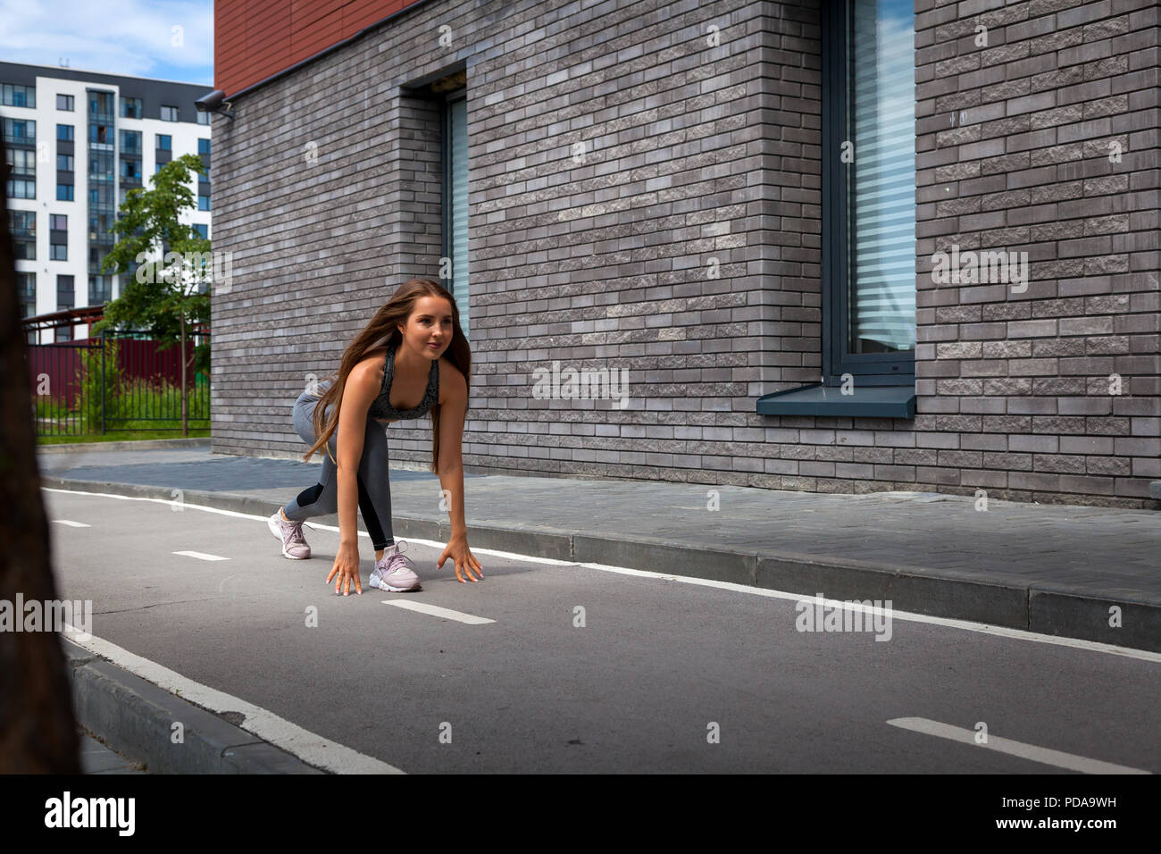 A young athletic woman stands in a low start for running in the stadium ...