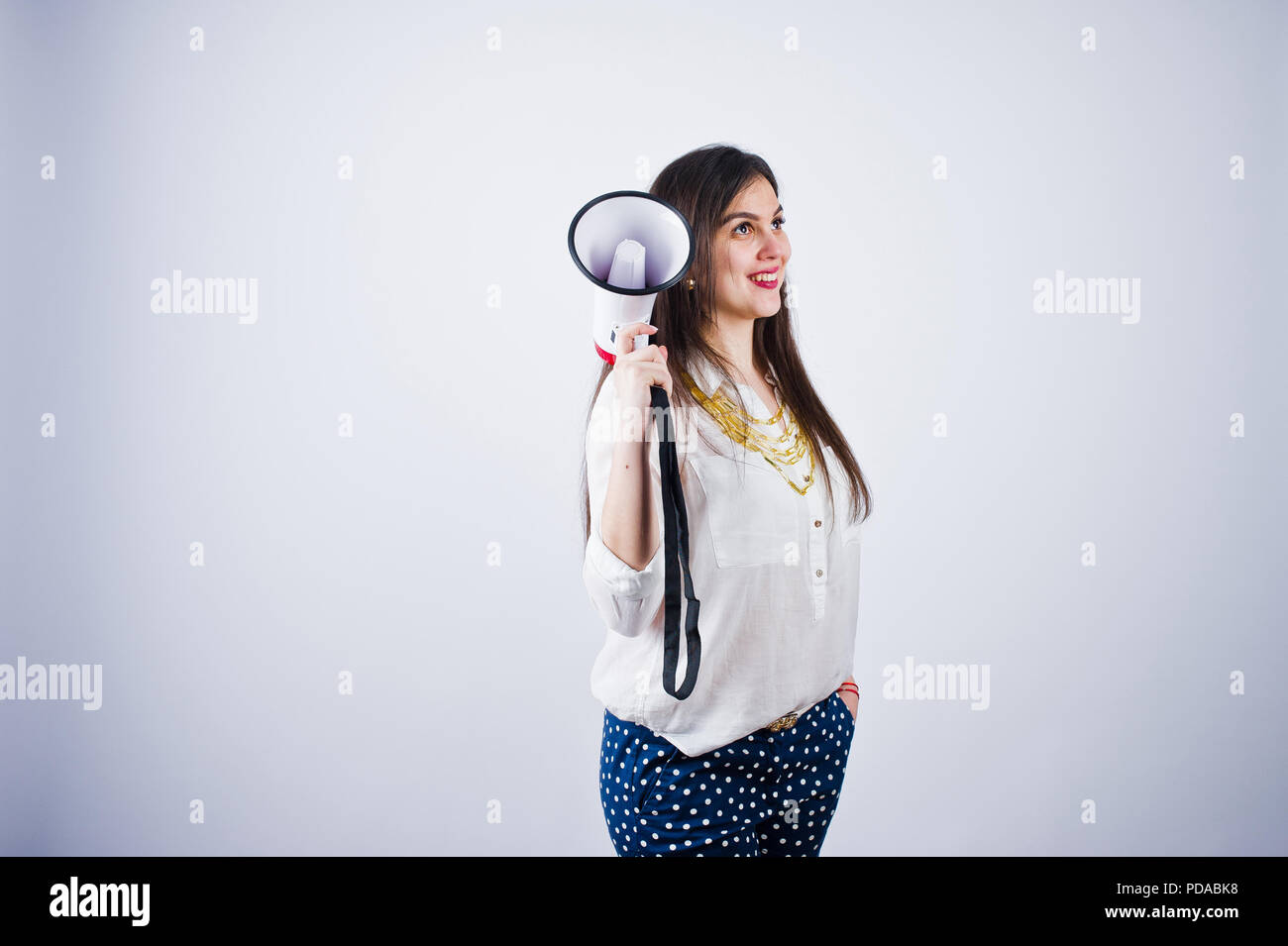Portrait of a young woman in blue trousers and white blouse posing with ...