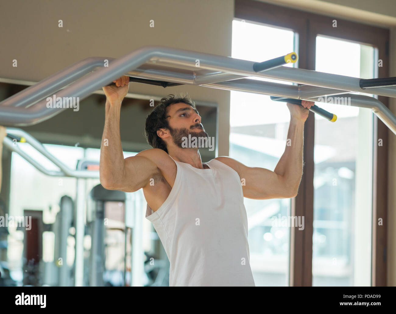 Man doing free body calisthenic pull-ups in a gym Stock Photo - Alamy