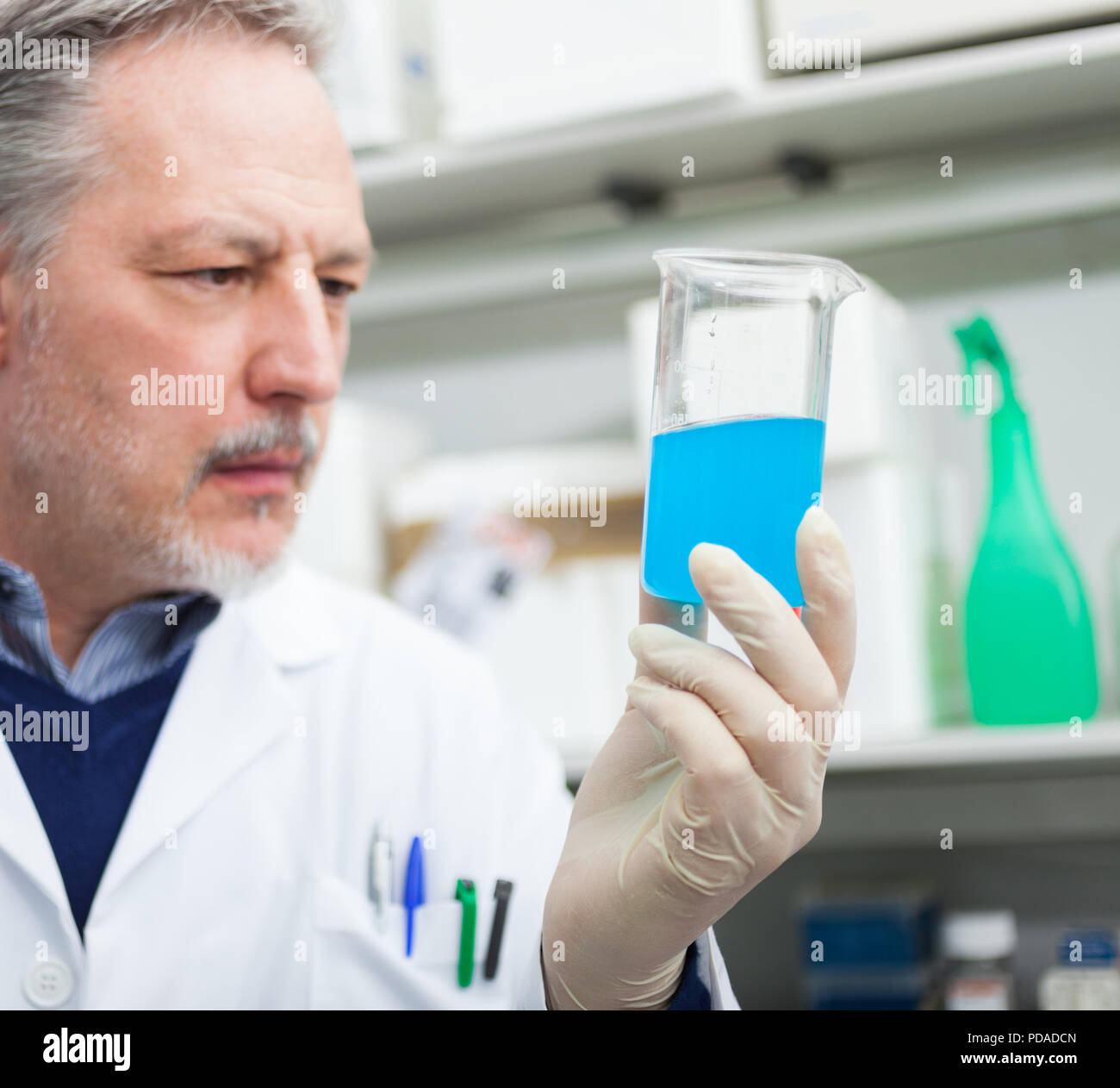 Close-up portrait of a male researcher holding a test tube with liquid ...