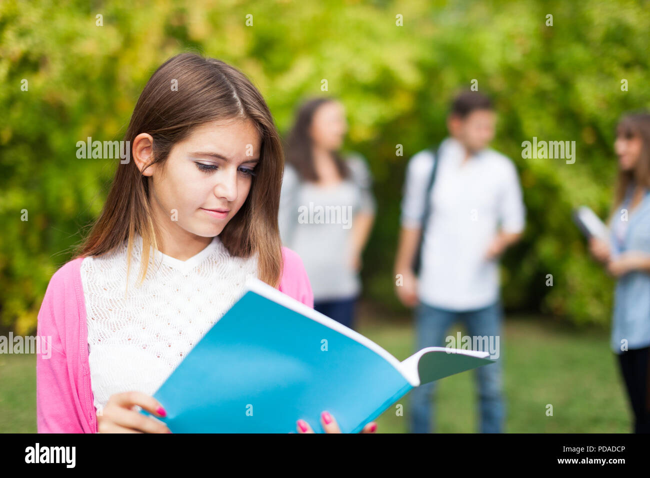 Outdoor portrait of a smiling young student in front of a group of ...