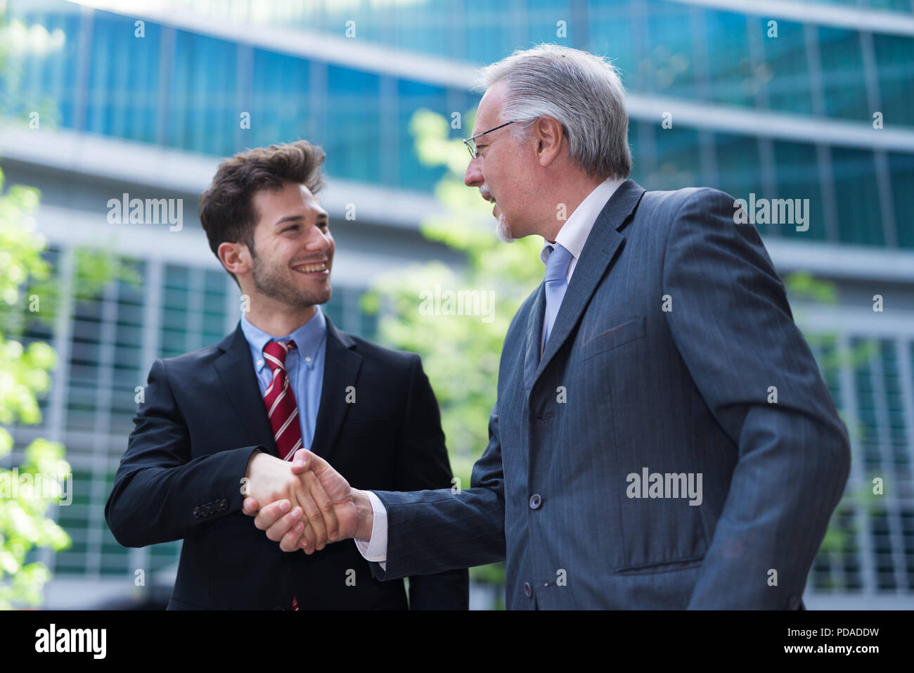Business people shaking hands in front of an office Stock Photo - Alamy