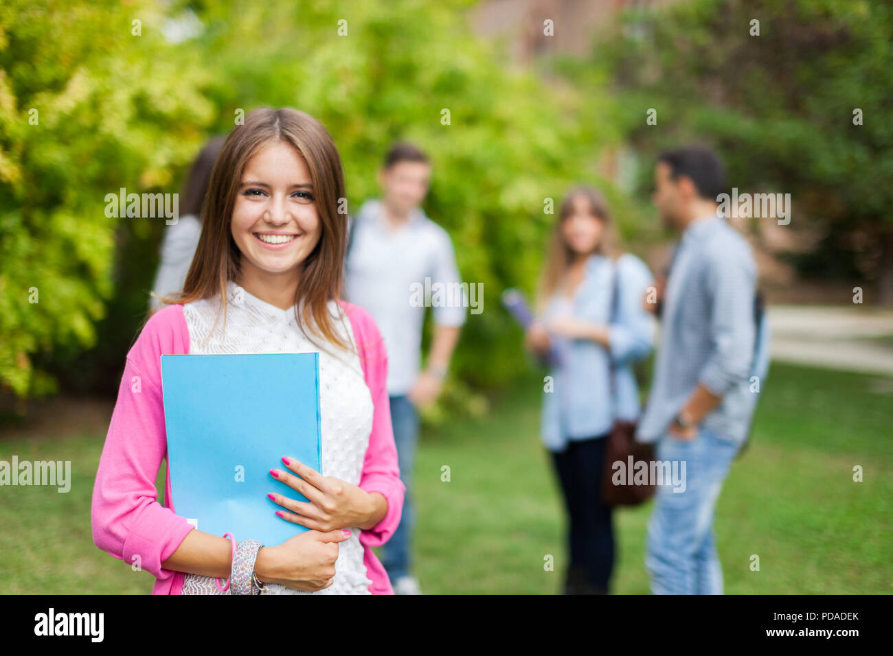 Outdoor portrait of a smiling young woman in front of a group of ...
