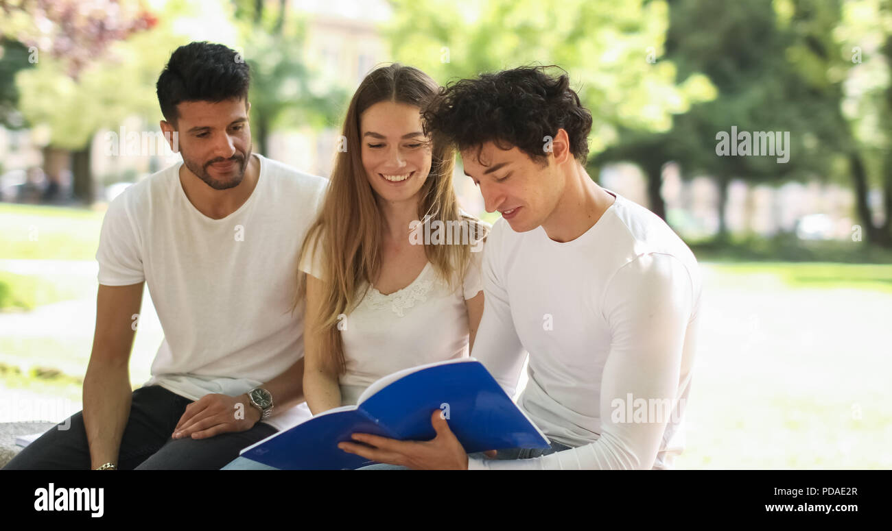 Three students studying together sitting on a bench outdoor Stock Photo ...