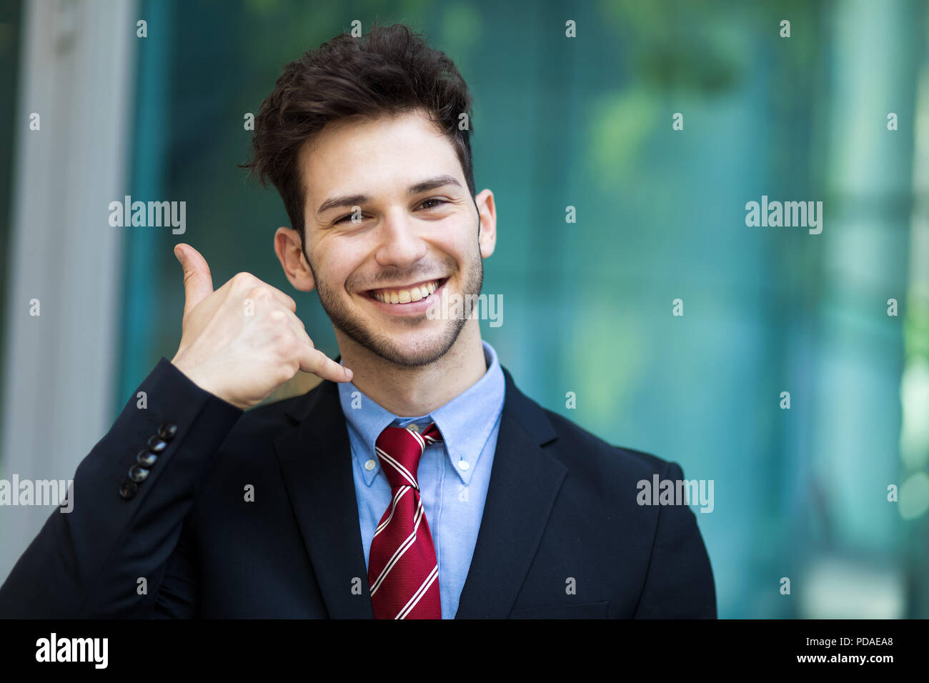 Businessman making a call me sign and smiling Stock Photo - Alamy