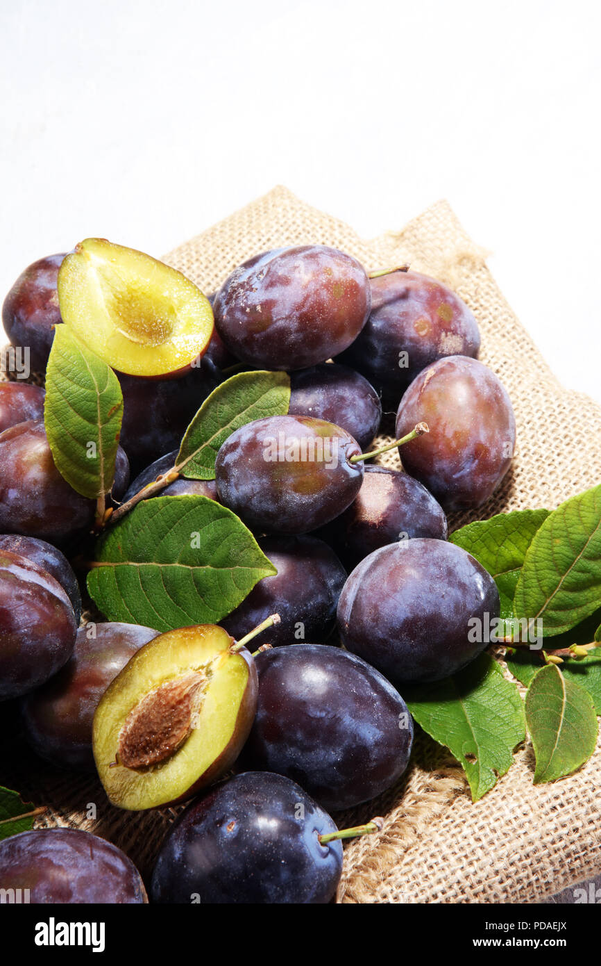 Plums on rustic background. Half of blue plum fruit. Many beautiful ...