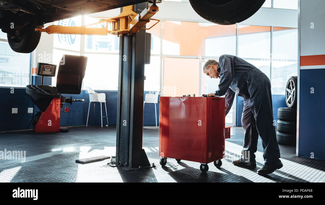Mechanic working in the garage and looking for tools in toolbox ...