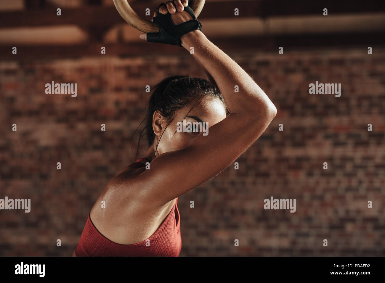 Strong young woman holding gymnast rings at the gym and staring at ...