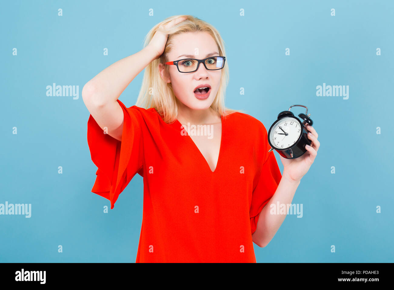 Blonde woman holding alarm clock Stock Photo - Alamy