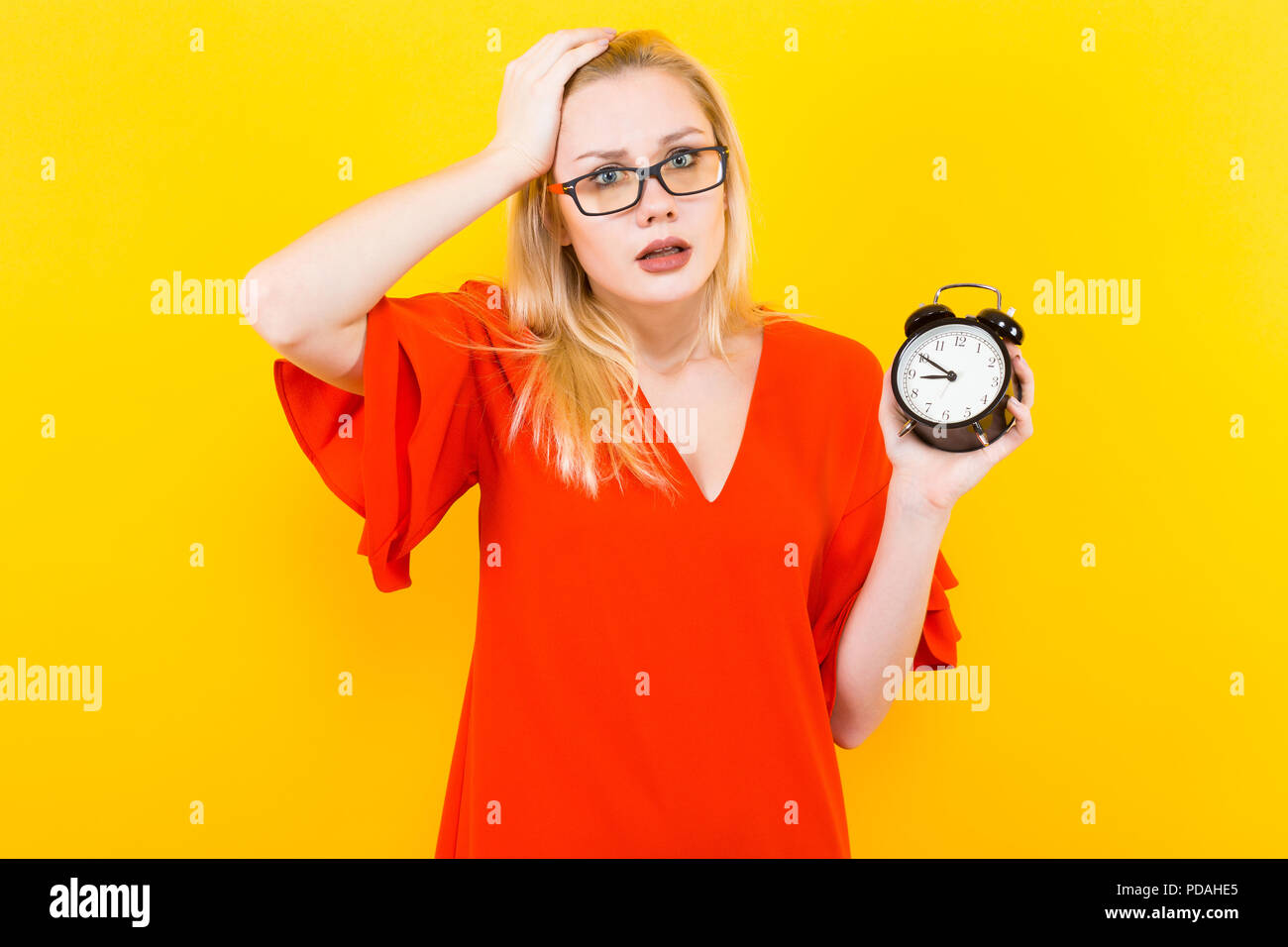 Blonde woman holding alarm clock Stock Photo - Alamy