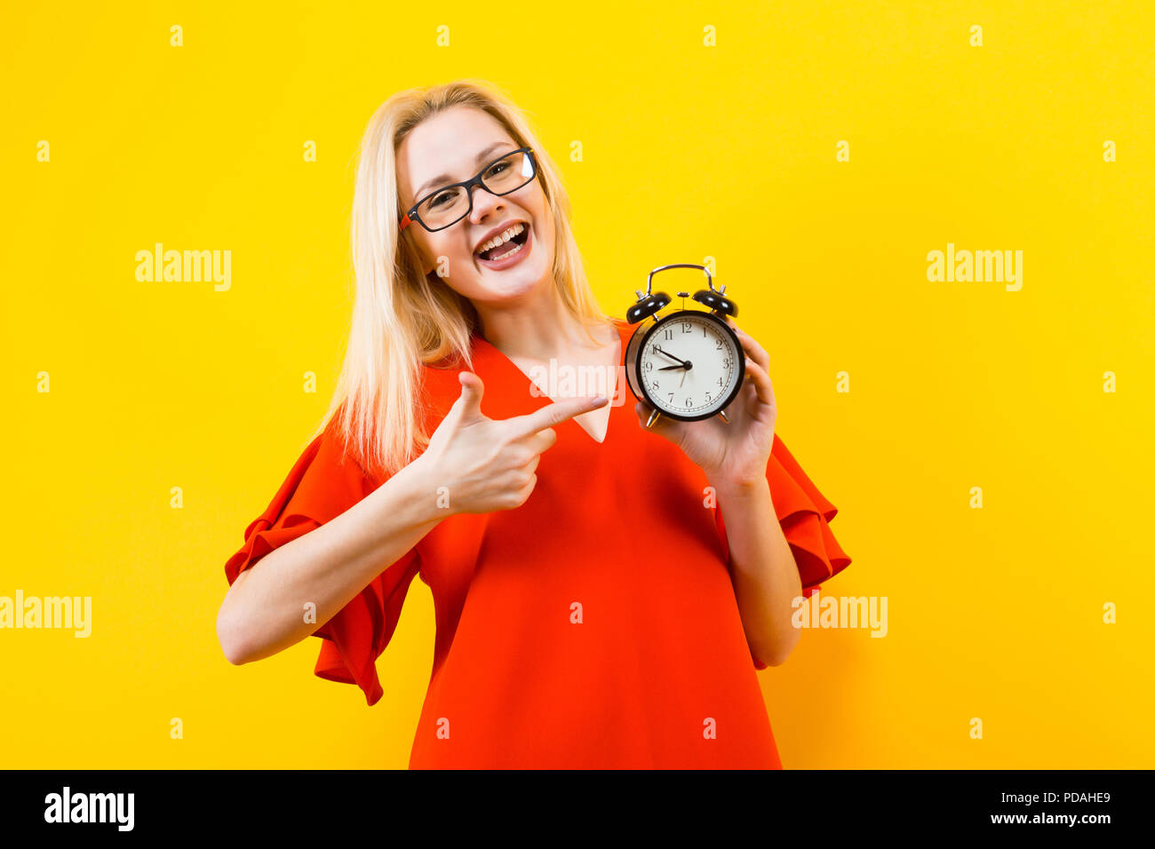 Blonde woman holding alarm clock Stock Photo - Alamy
