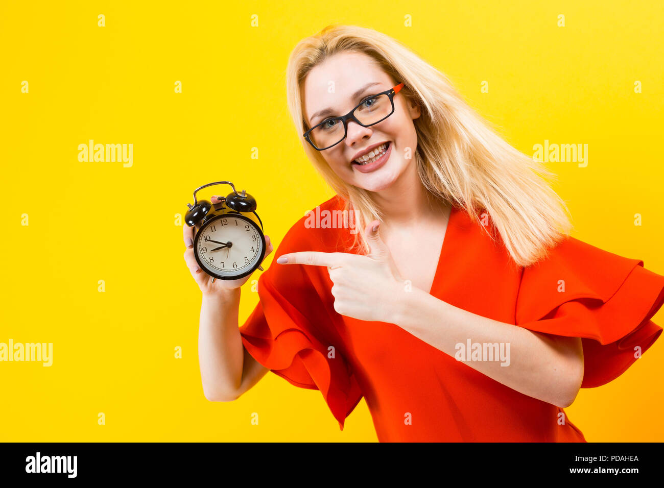 Blonde woman holding alarm clock Stock Photo - Alamy
