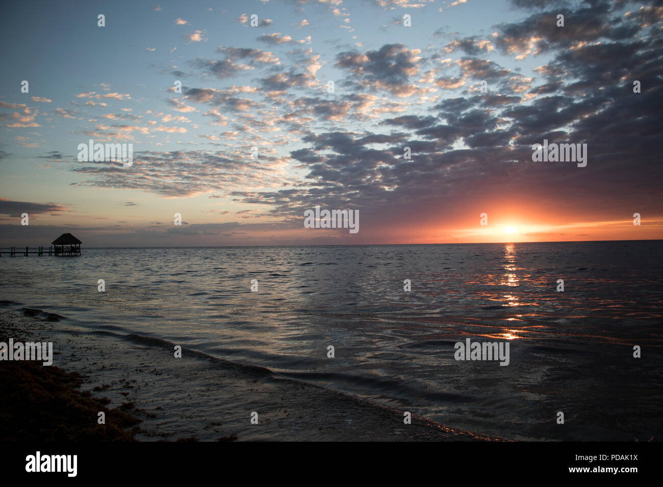 Sun rising over the ocean reflecting in the water with clouds and a ...