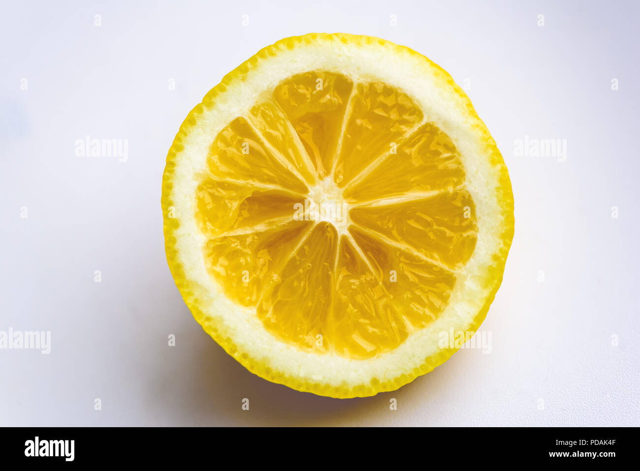 Slice of a bright yellow lemon on a white background with close up of ...