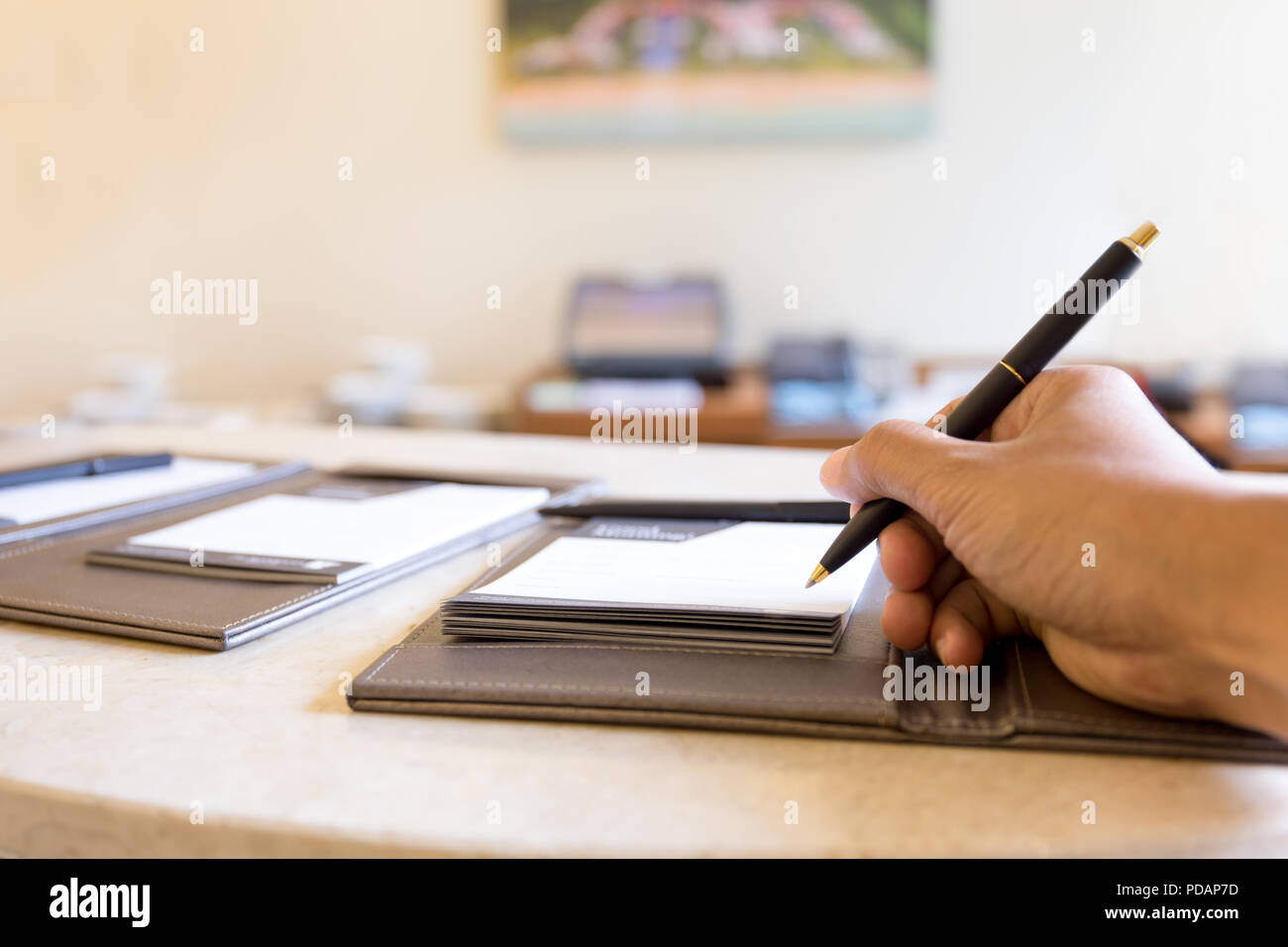 Hand with pen filling application form on table Stock Photo - Alamy