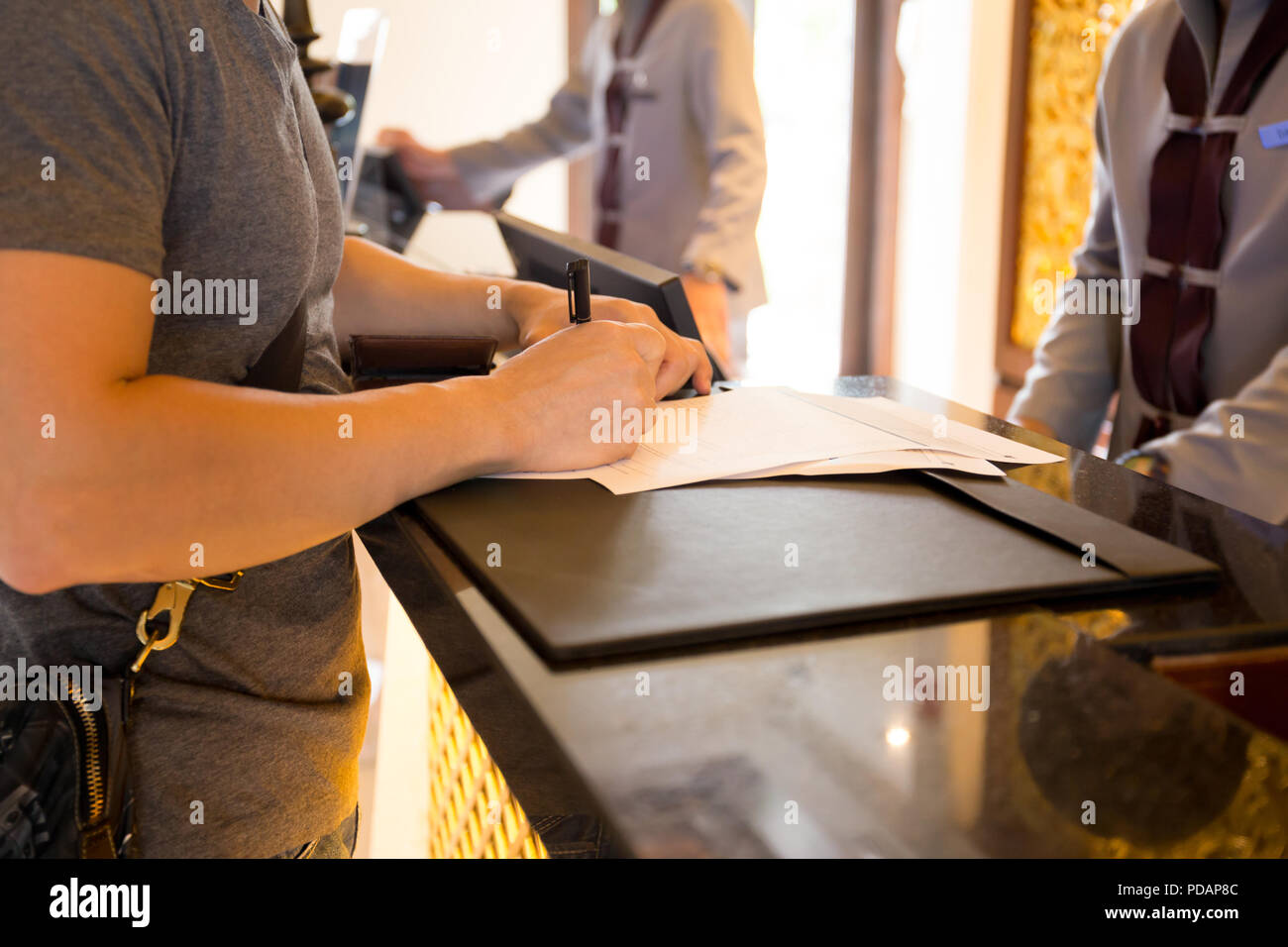 Male guest check in at hotle signing a form at reception counter Stock ...