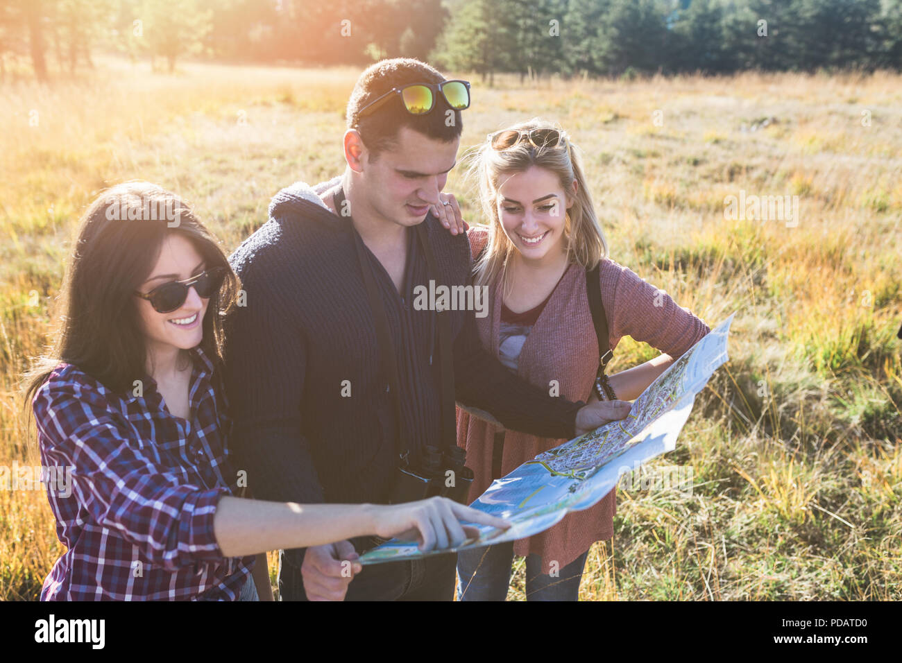 Young friends enjoying outdoor, standing in deep grass, smiling and ...