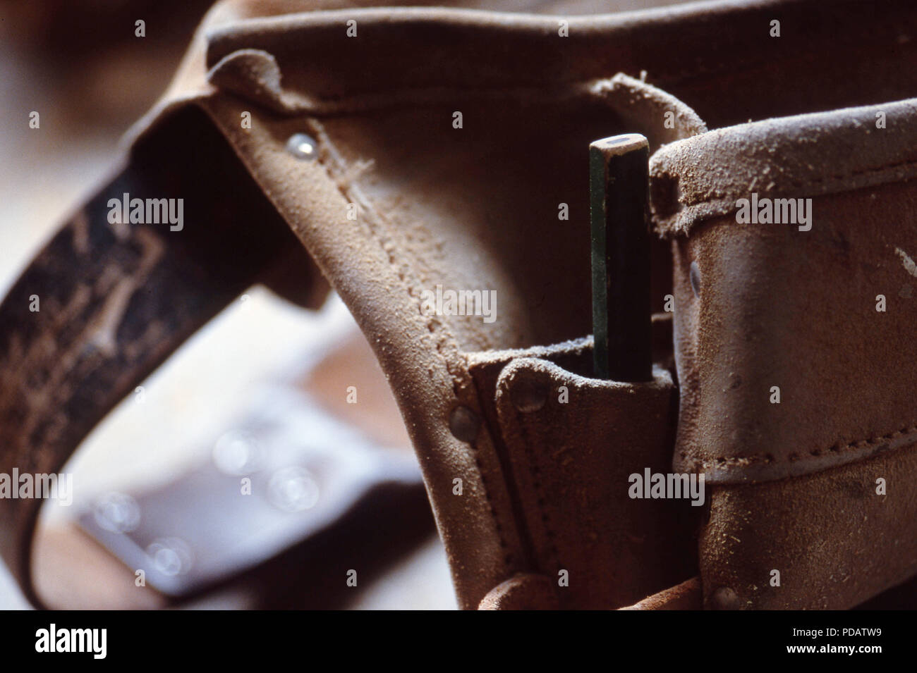 Well-used leather tool belt with old fashioned pencil at a construction ...