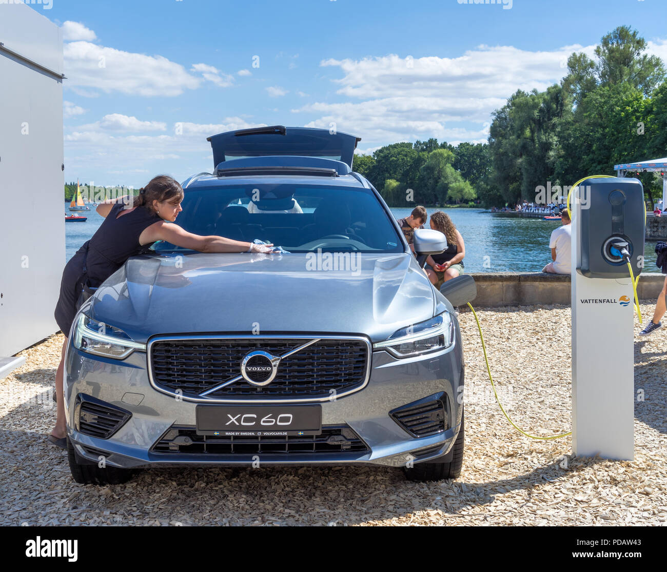 Young woman cleaning the windscreen of an electrically powered Volvo XC ...