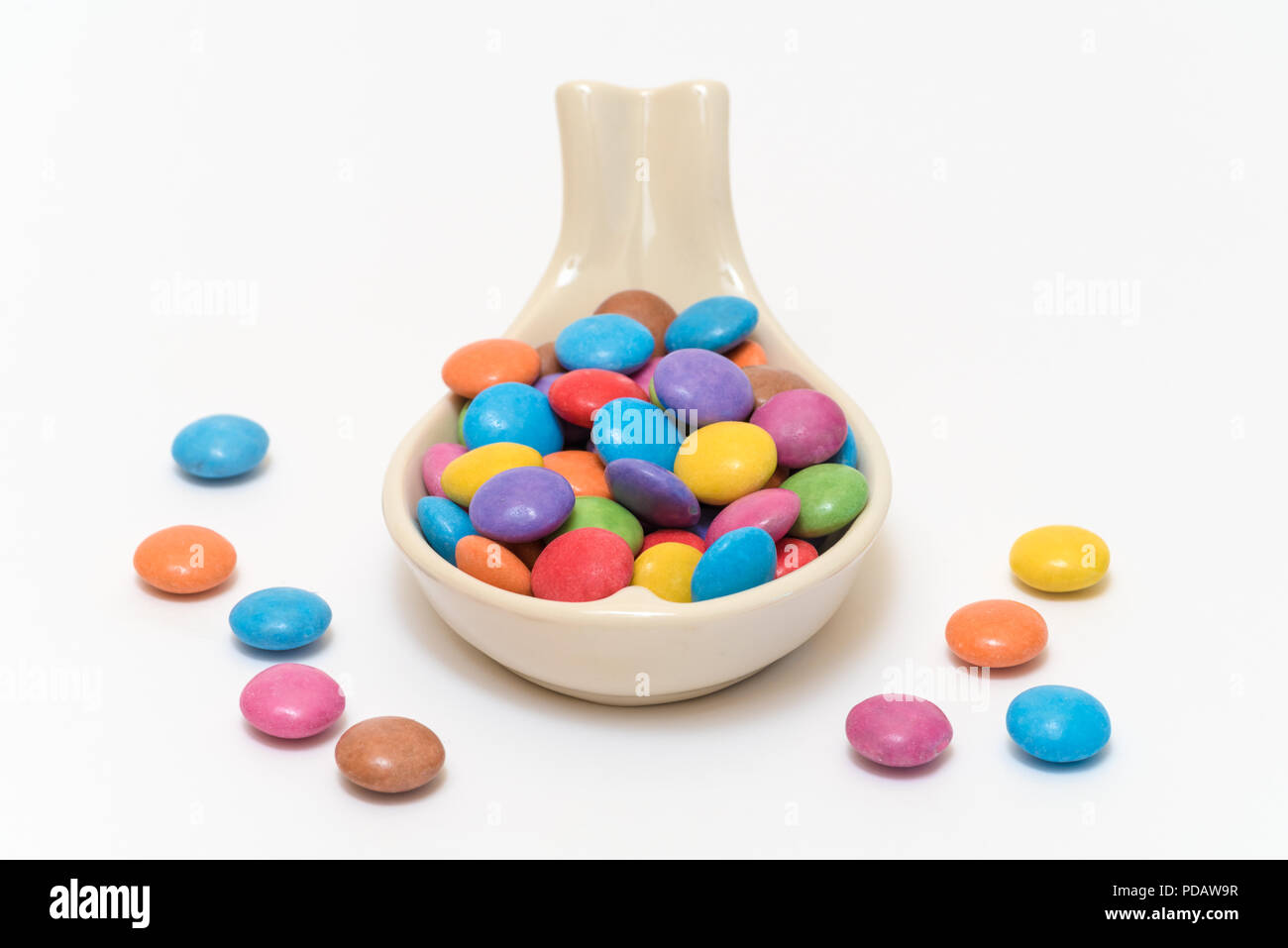 Multi-colored smarties candies on a china spoon isolated on a white ...