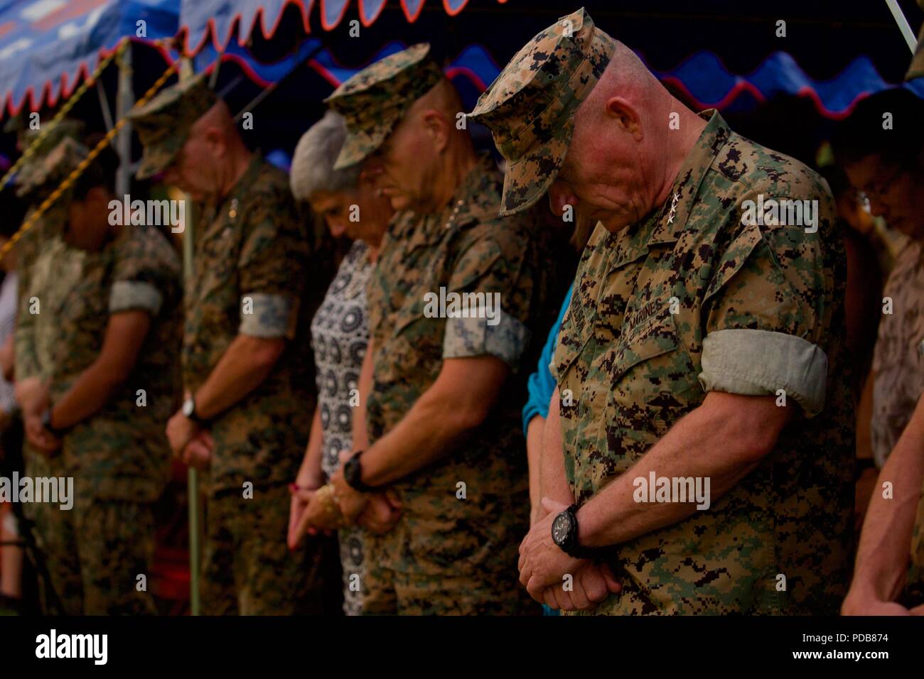 Service members, families, and distinguished guests bow their heads in ...