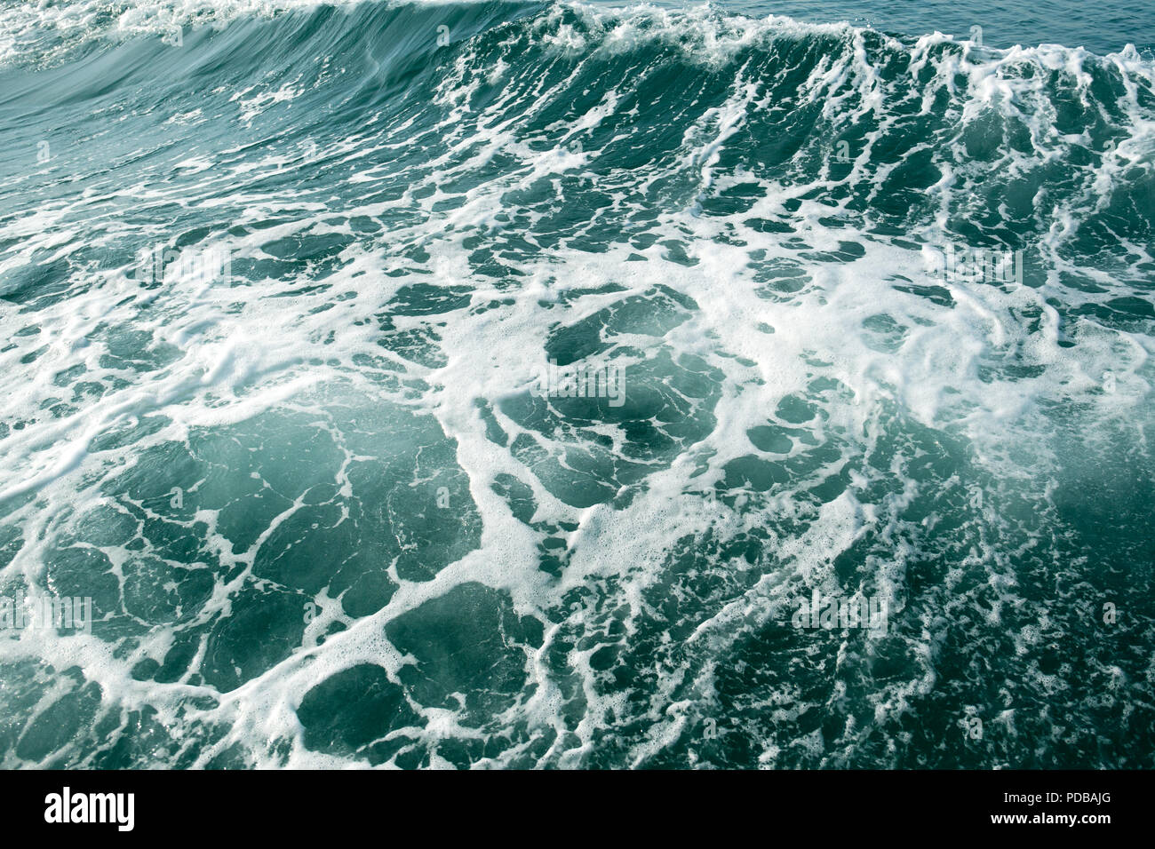 Deep green ocean wave with mountain and sky in background Stock Photo ...