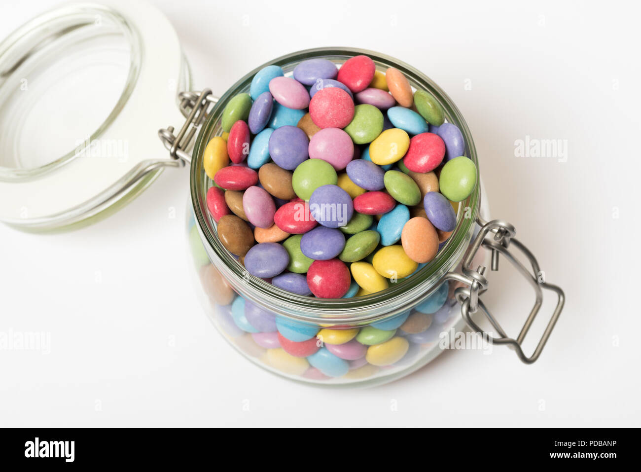 Glass food storage jar with open lid and full of colorful smarties ...