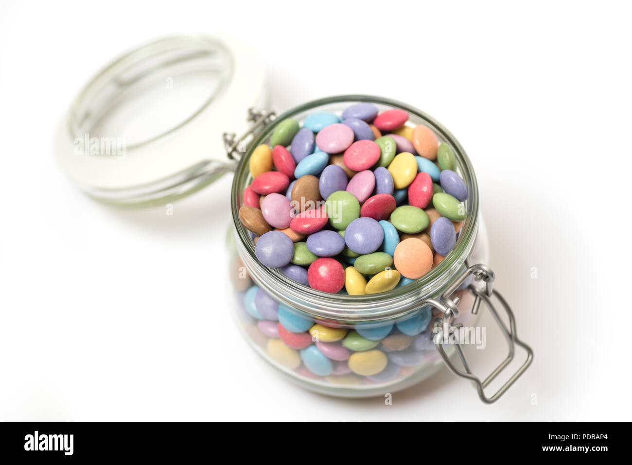 Glass food storage jar with open lid and full of colorful smarties ...