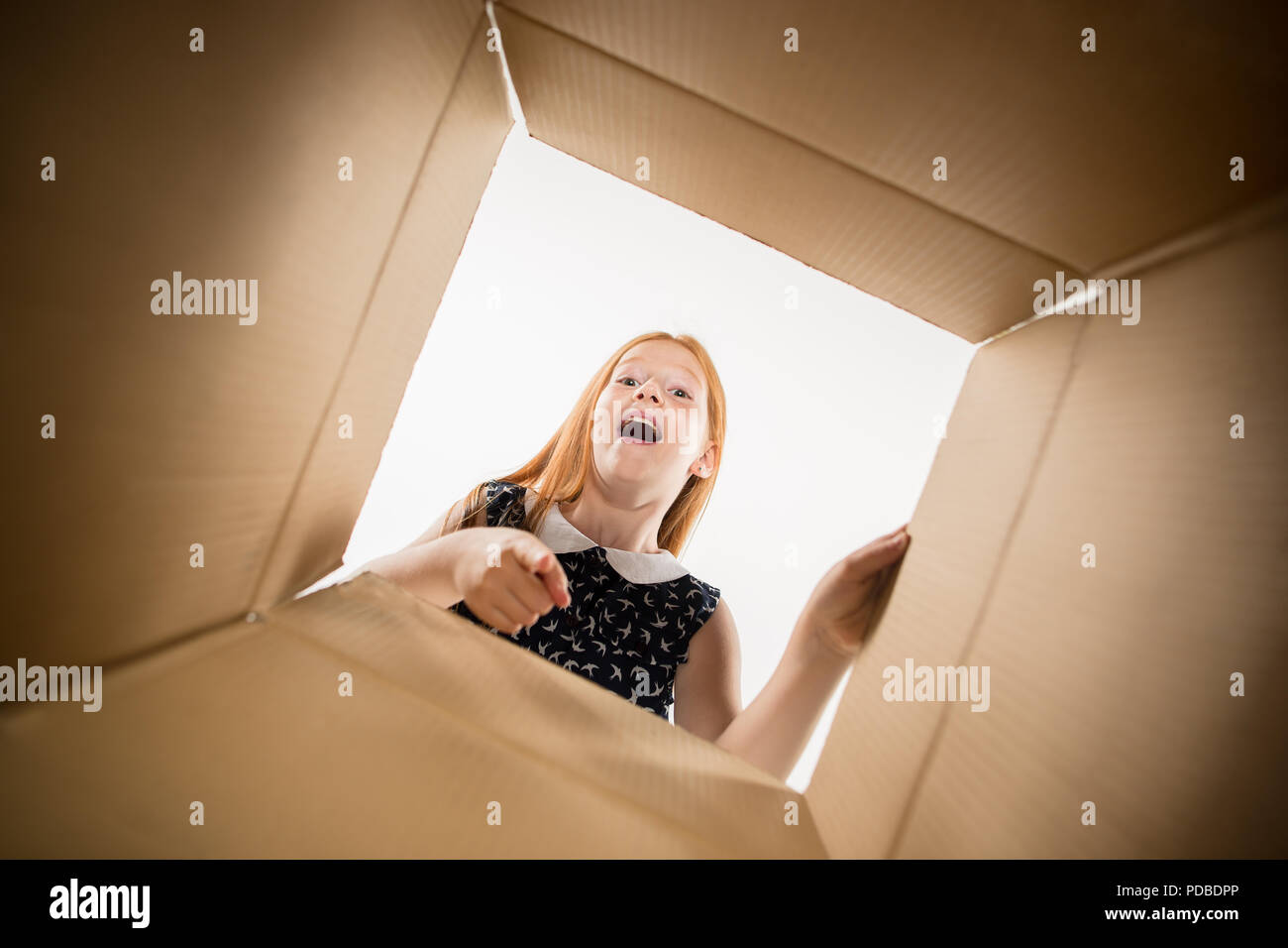The surprised girl unpacking, opening carton box and looking inside ...