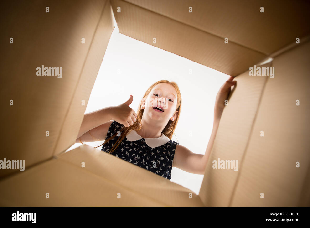 The surprised girl unpacking, opening carton box and looking inside ...