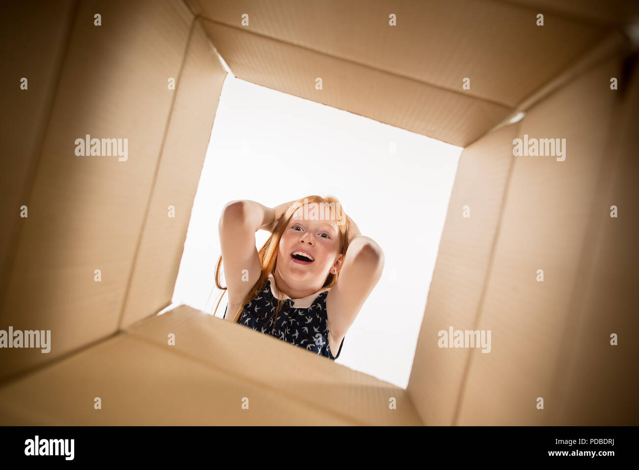 The surprised girl unpacking, opening carton box and looking inside ...