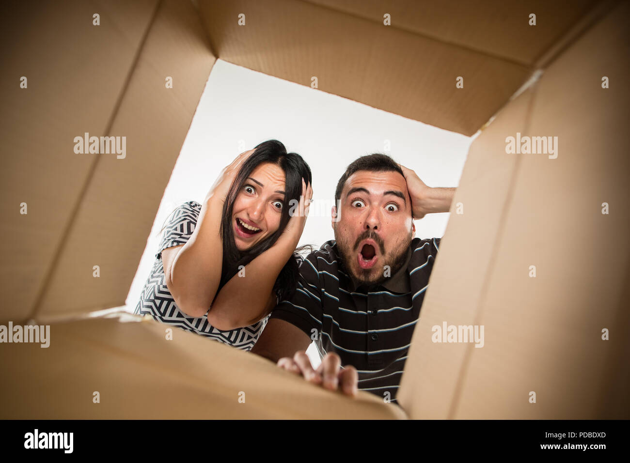 The surprised man and woman unpacking, opening carton box and looking ...