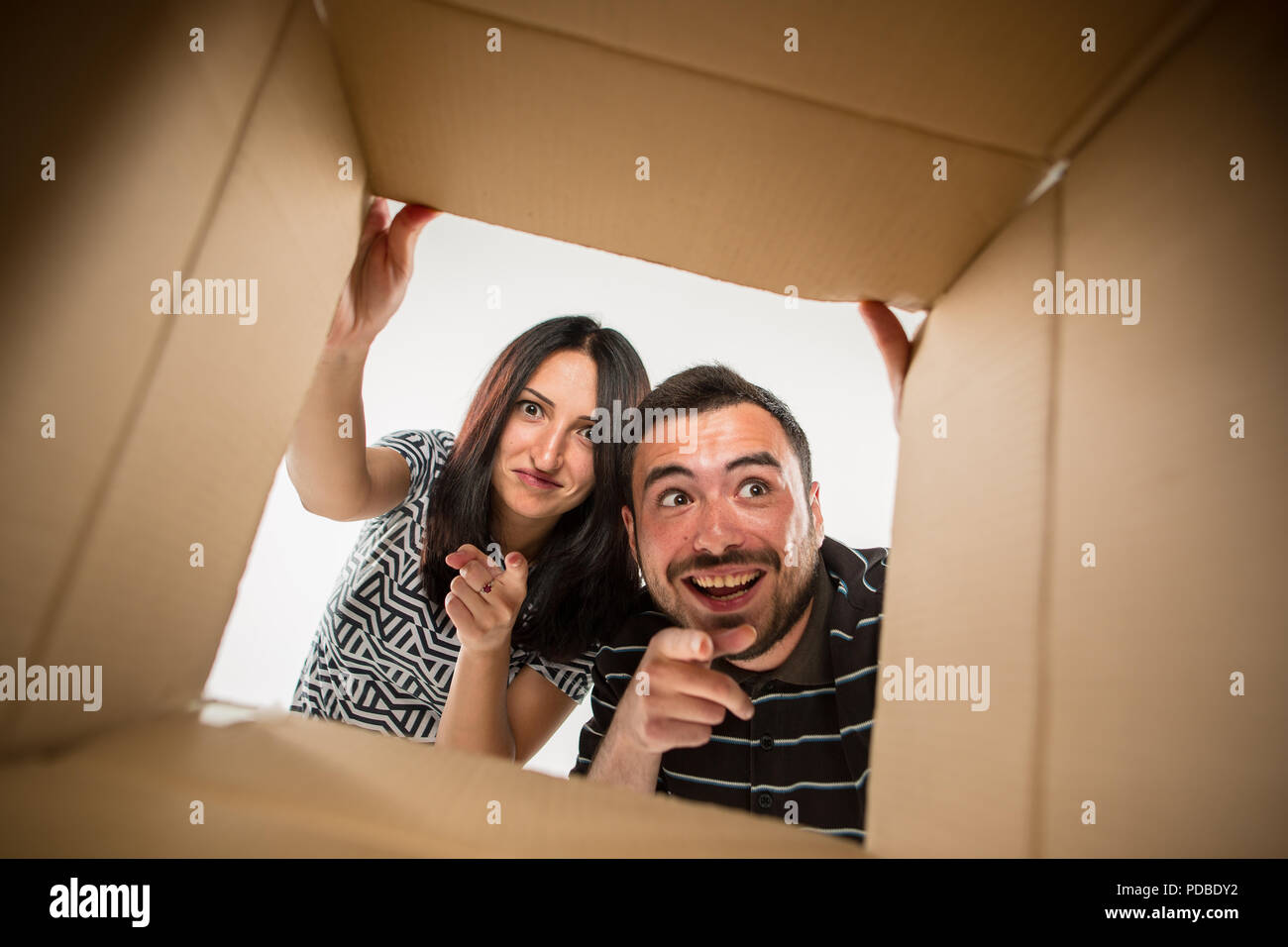The surprised man and woman unpacking, opening carton box and looking ...