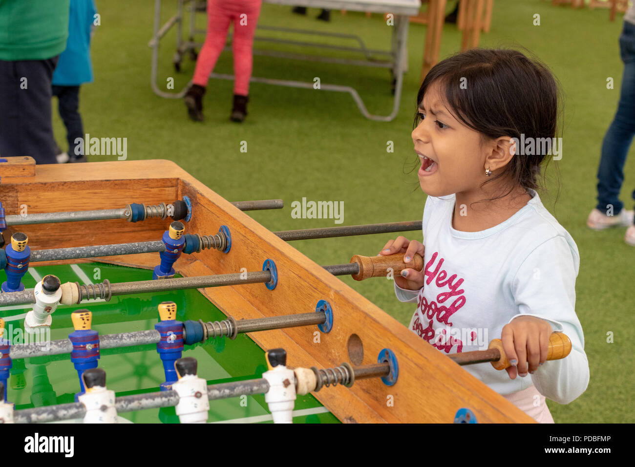 Cute little girl playing table football in the park Stock Photo - Alamy