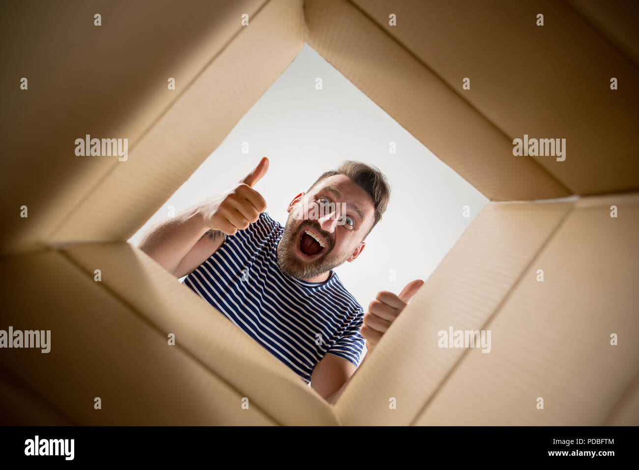 The surprised man unpacking, opening carton box and looking inside. The ...