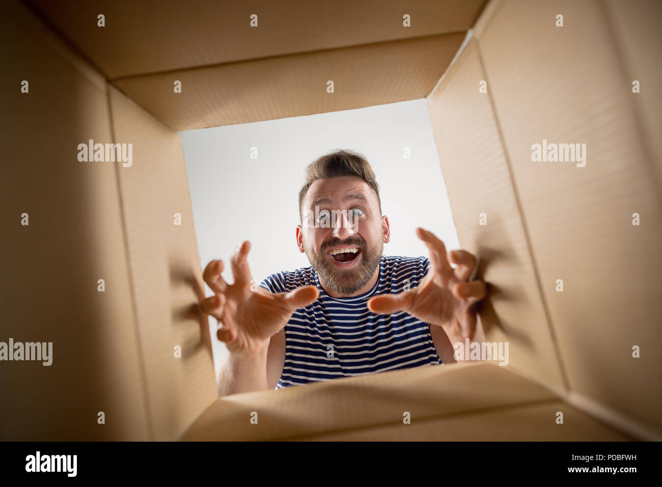 The surprised man unpacking, opening carton box and looking inside. The ...