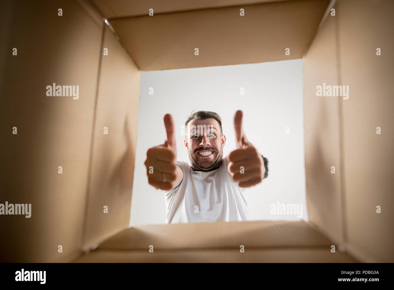 The surprised man unpacking, opening carton box and looking inside. The ...