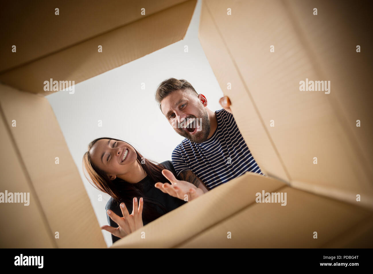 The surprised man and woman unpacking, opening carton box and looking ...