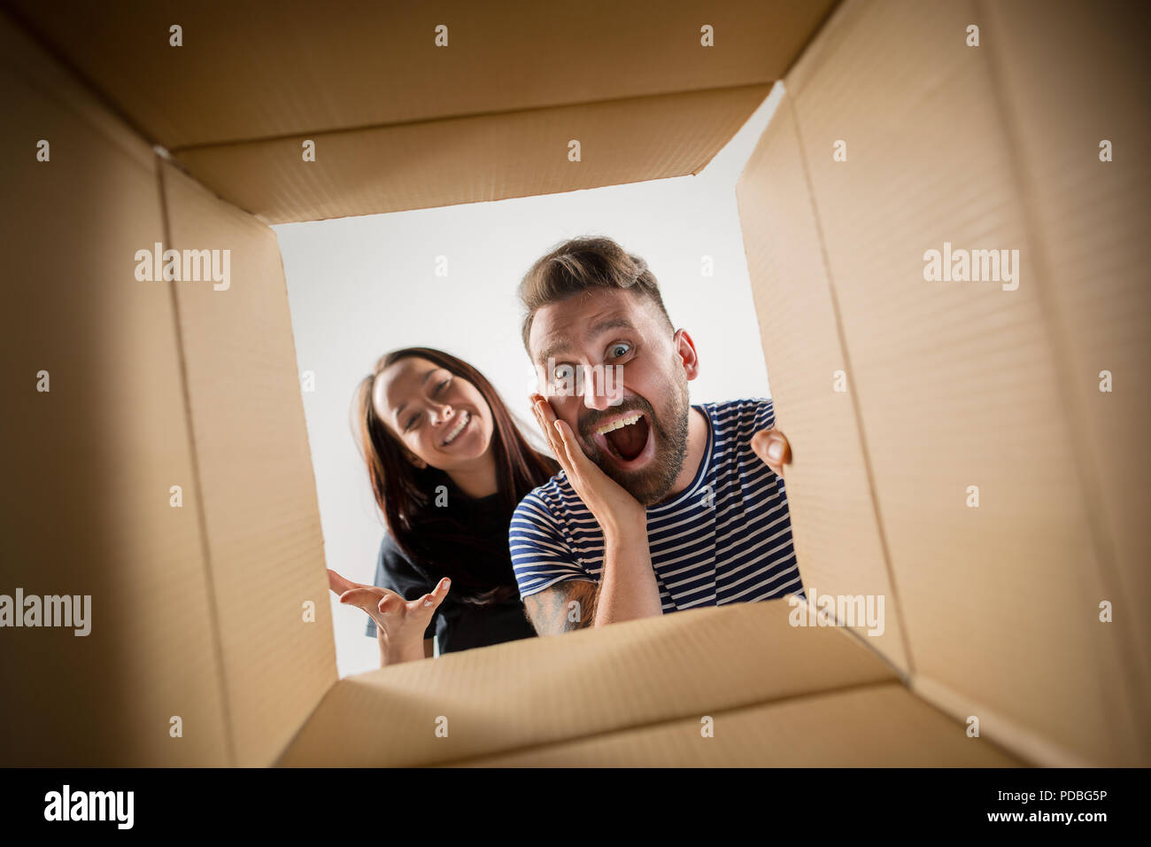 The surprised man and woman unpacking, opening carton box and looking ...