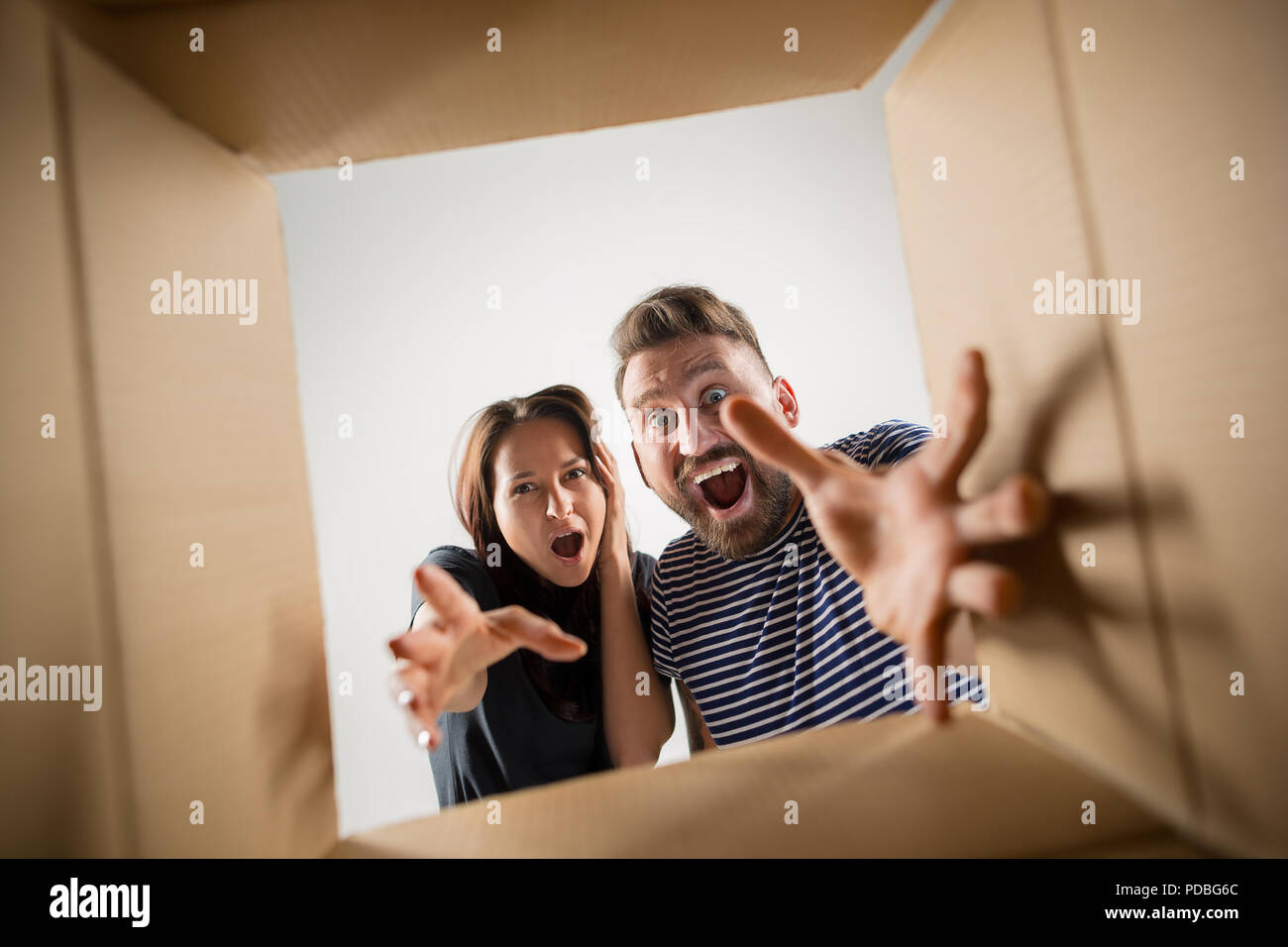 The surprised man and woman unpacking, opening carton box and looking ...