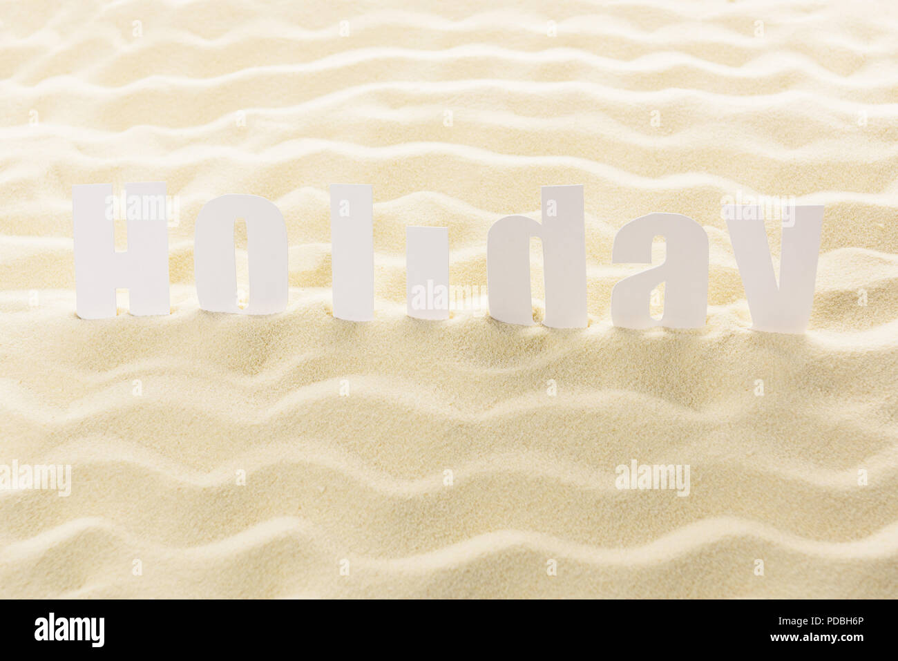 Word Holiday on sandy beach waves Stock Photo - Alamy
