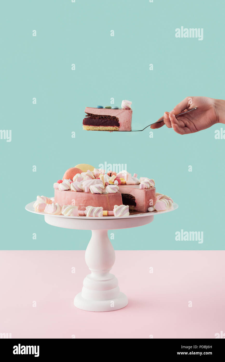 cropped view of woman holding piece of cake on shovel over big cake on ...