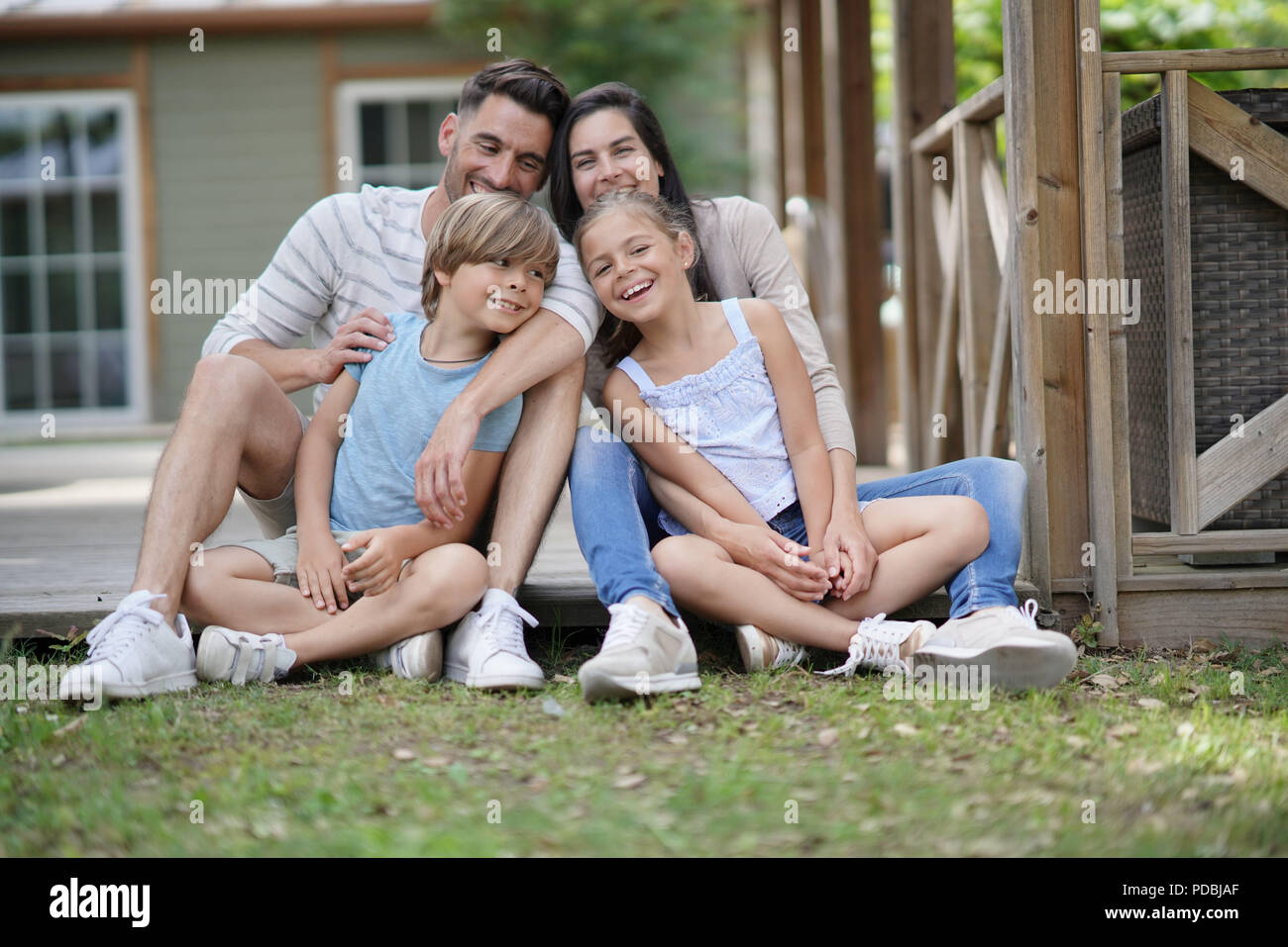 Happy family of four sitting in yard Stock Photo - Alamy