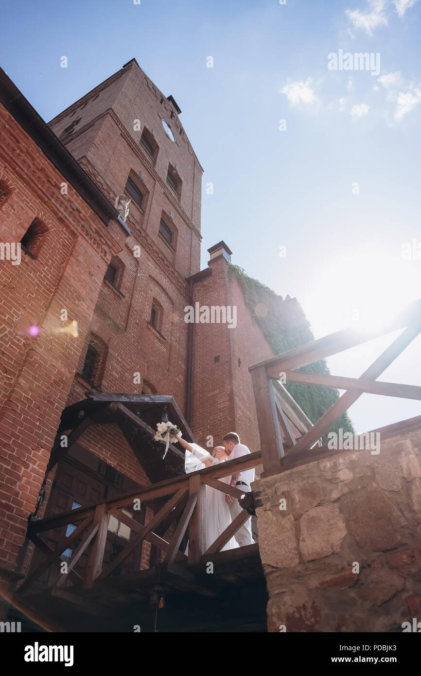 bottom view of bride and groom kissing in front of entrance to ancient ...