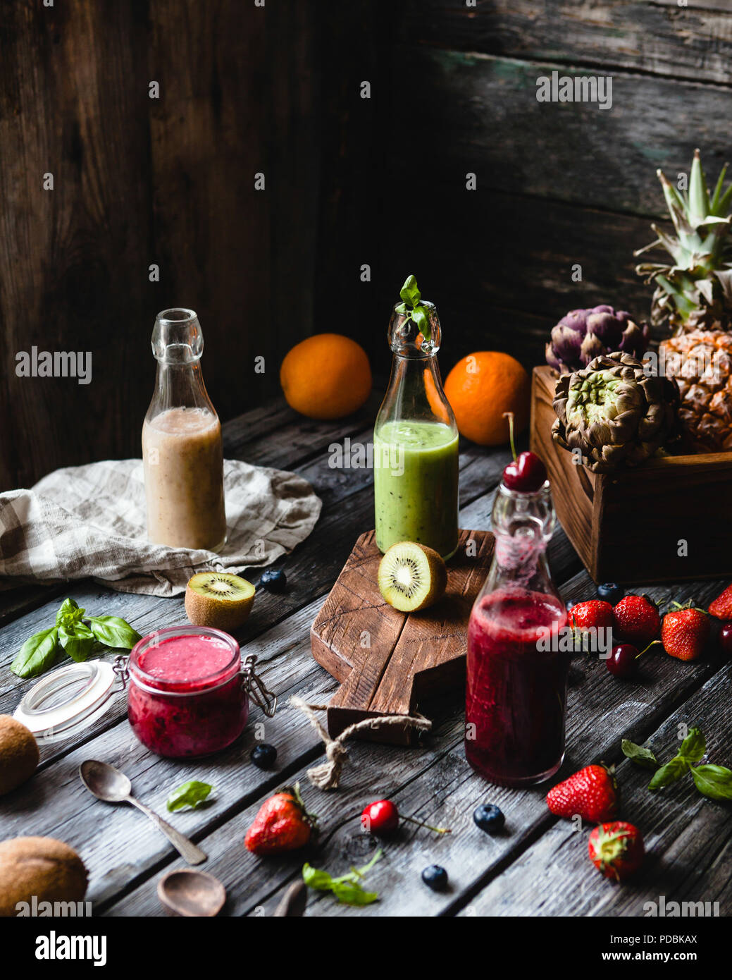 Fresh healthy smoothies in glass bottles on rustic table with assorted ...