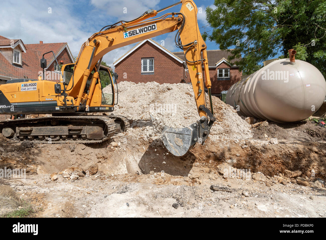 A Excuvator crawler digging a trench for an underground tank on a ...
