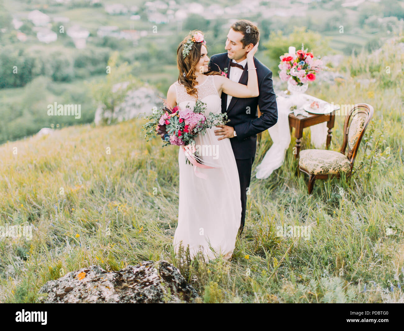 Horizontal outdoor portrait of the groom hugging the bride while she is ...