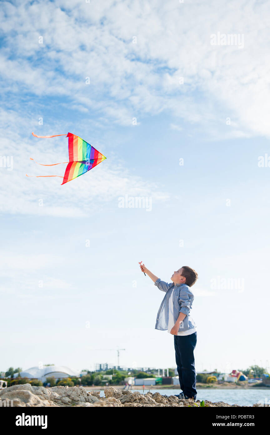 happy caucasian little kid playing with flying kite near sea shore at ...