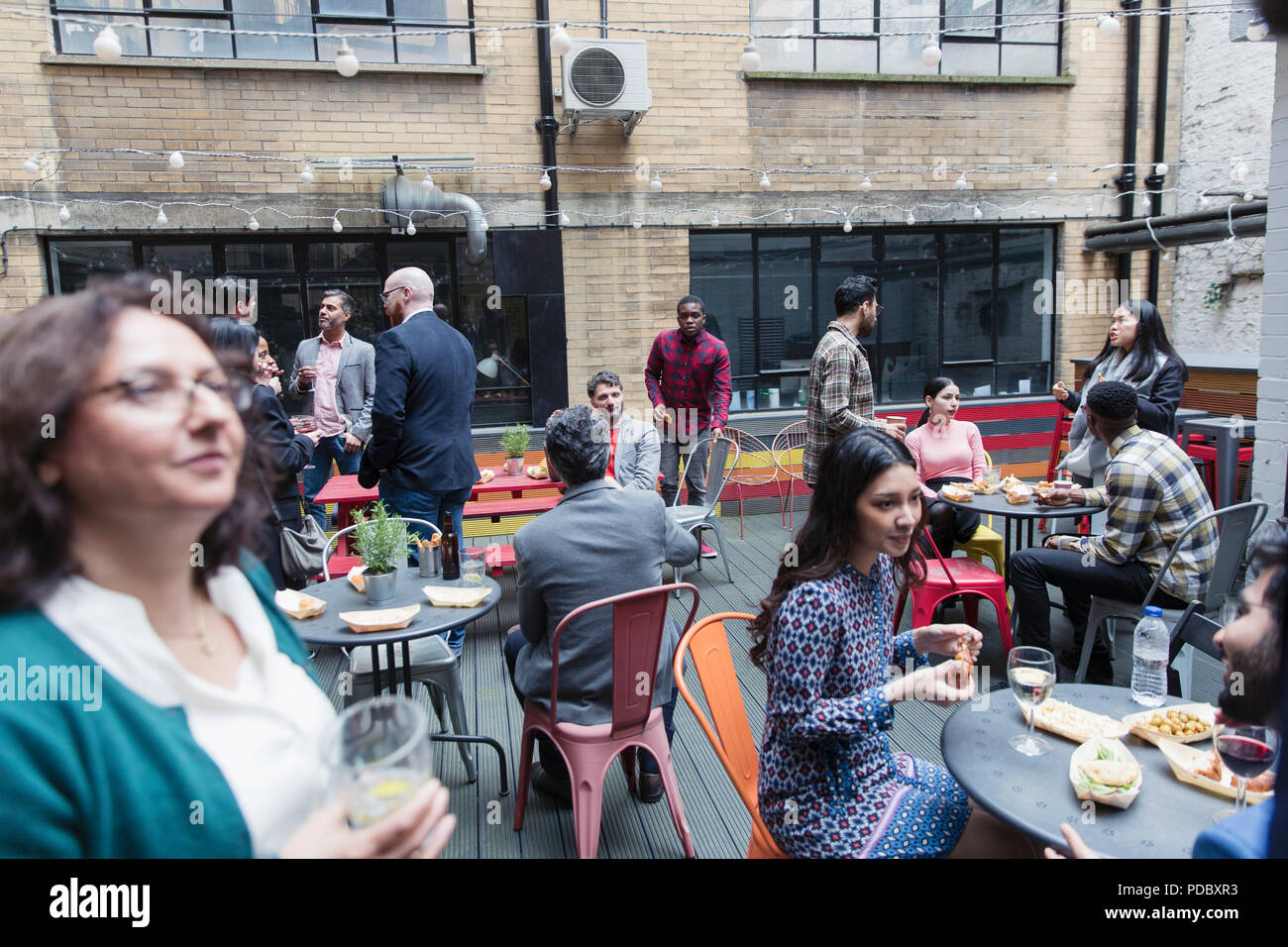 Friends socializing, eating and drinking at party on patio Stock Photo ...